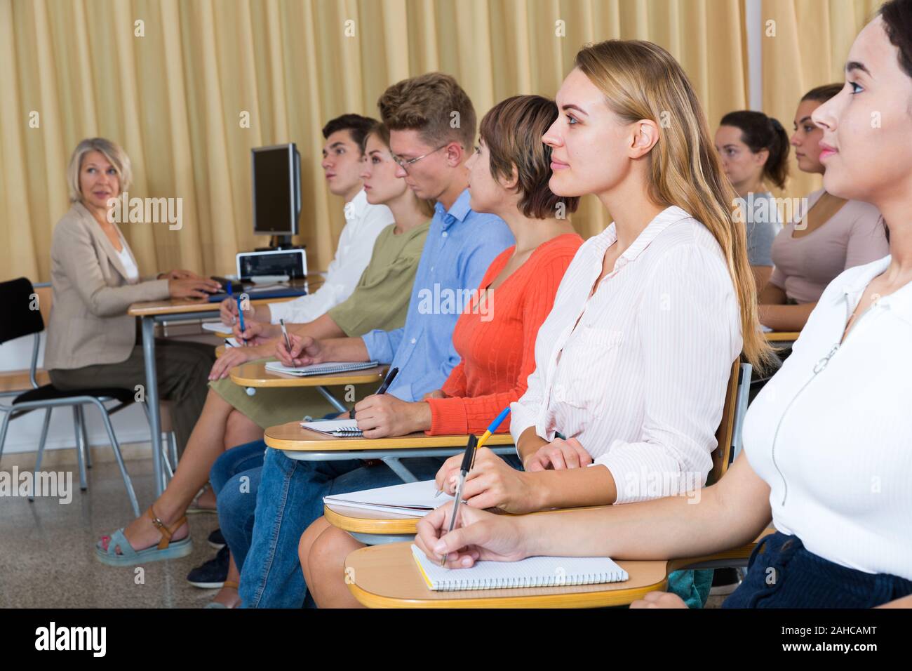 Side view of student group working with female teacher on lecture in ...