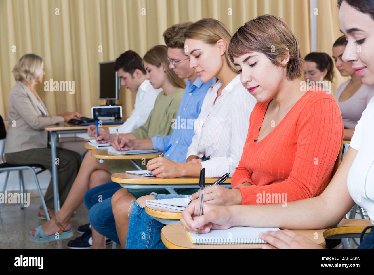 Side view of student group working with female teacher on lecture in ...