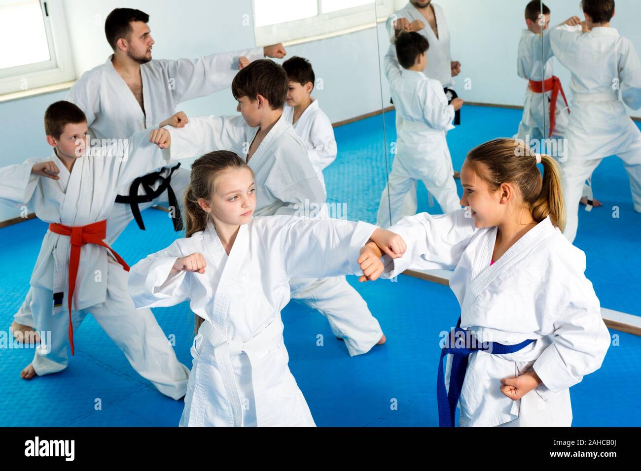 Glad children training in pairs to practice new technique at karate ...