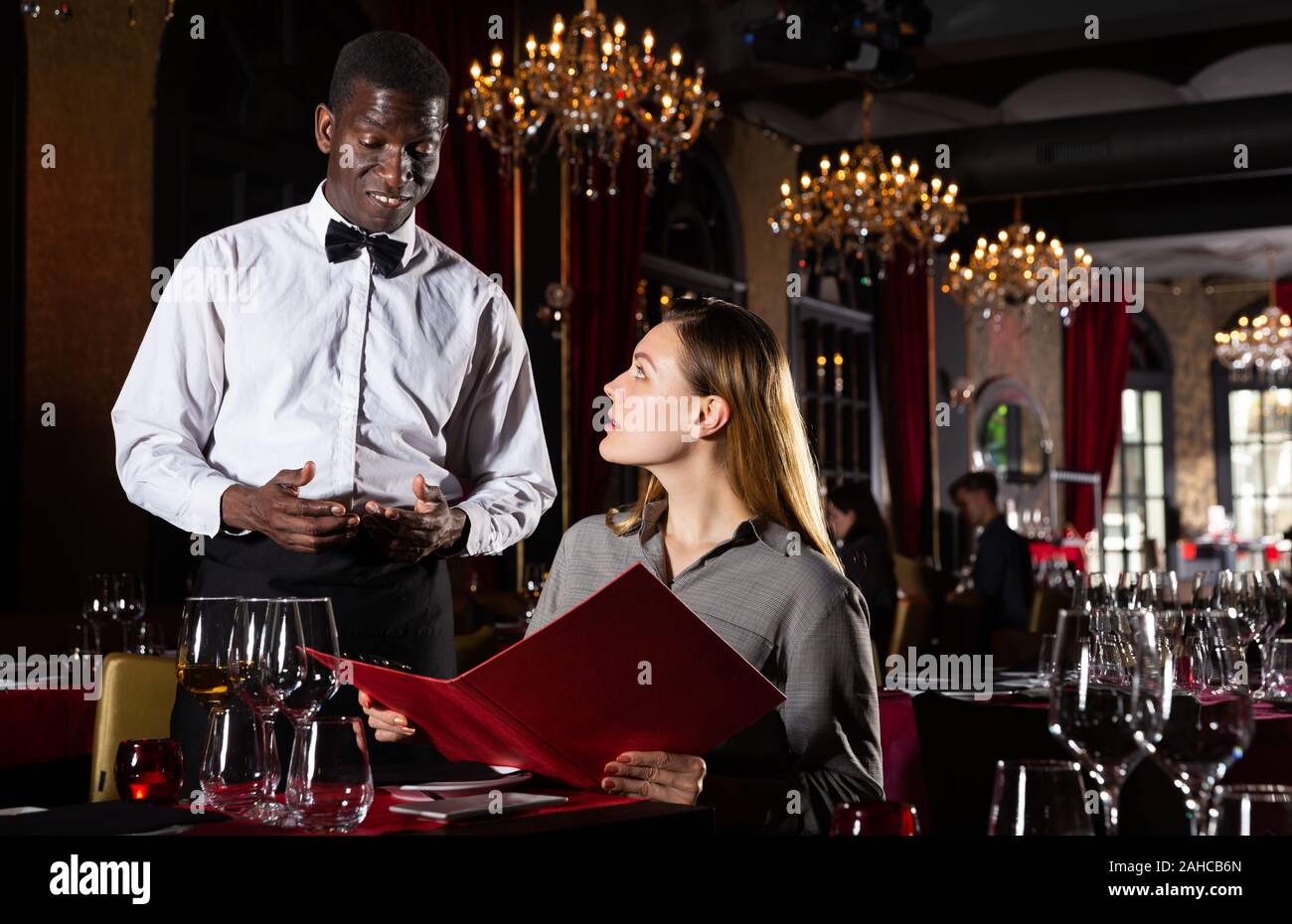 African-american waiter receiving order from guest in fashionable ...