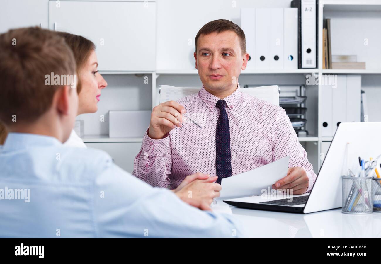 Middle-aged mother and son visiting consultation with school headmaster ...