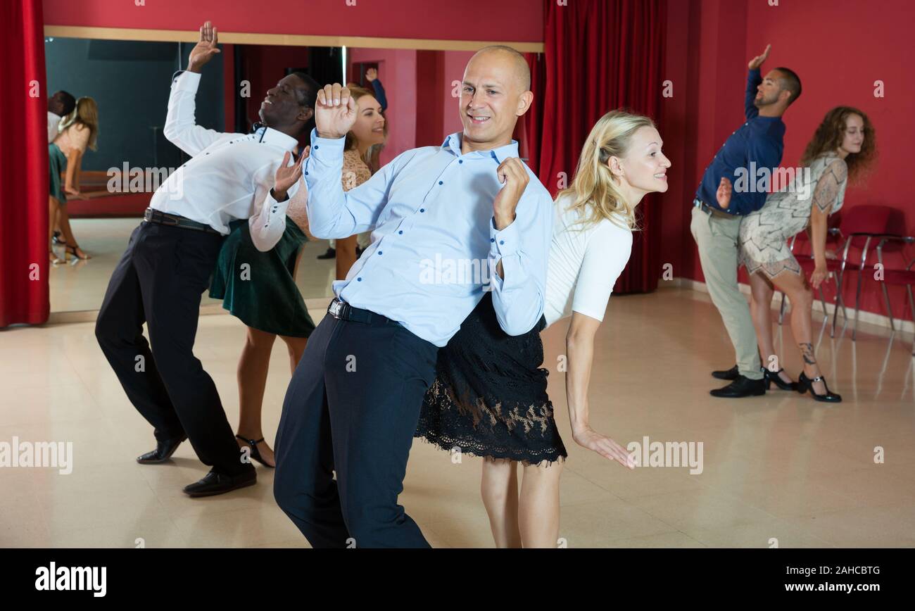 Young smiling people practicing vigorous jive movements in dance class ...