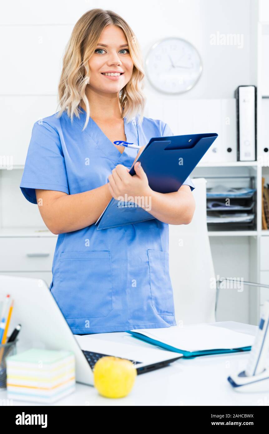 Kindly woman in doctor's uniform greets visitors at modern office Stock ...