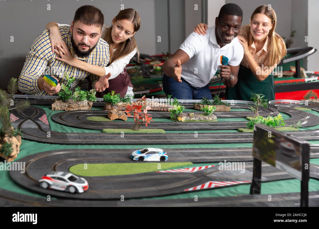 Two teams from couples play slot car racing game Stock Photo - Alamy