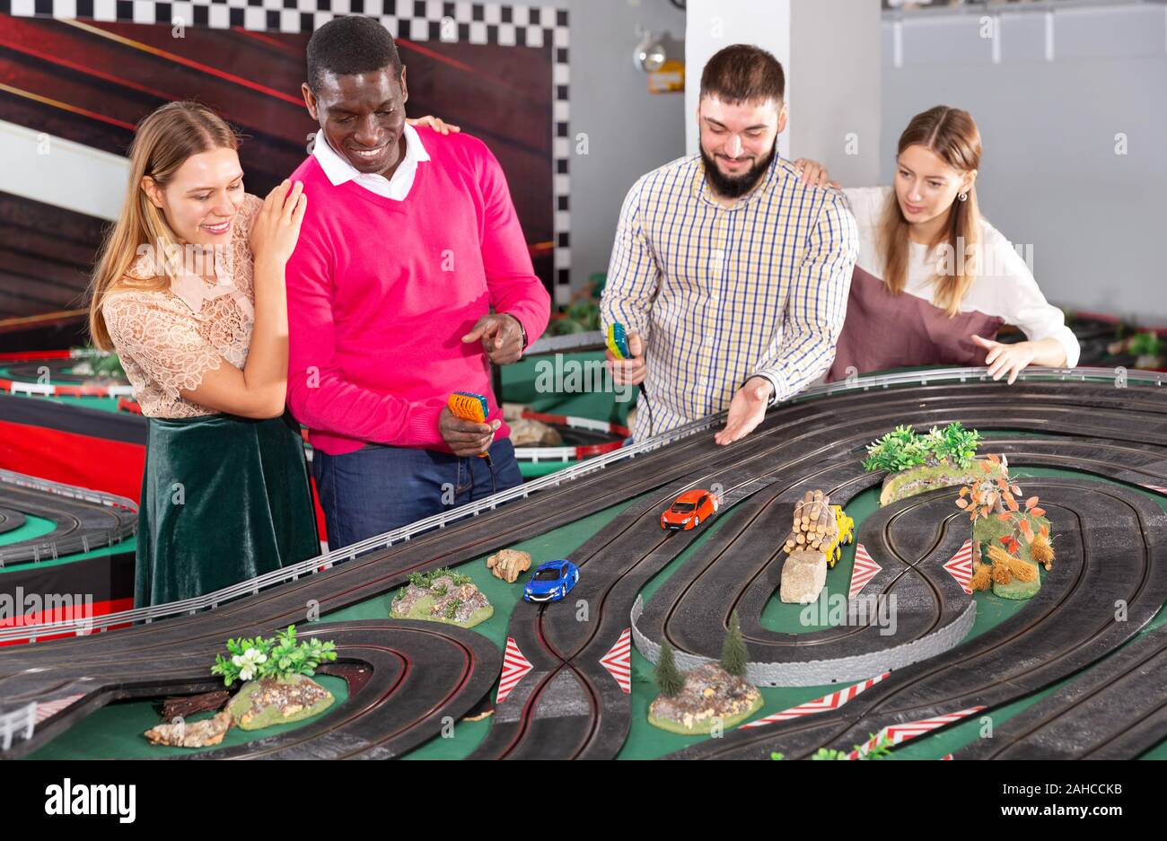 Girls with guys play together slot car racing models Stock Photo - Alamy