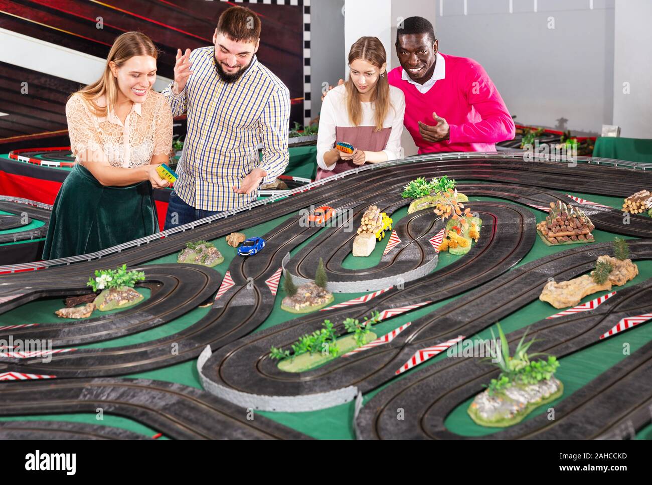 Girls with guys play together the slot car racing models Stock Photo ...