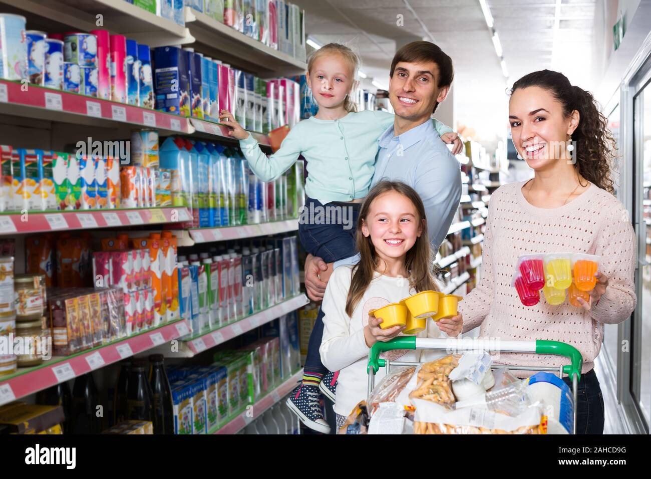 Cheerful young family with two little daughters purchasing yoghurts in ...