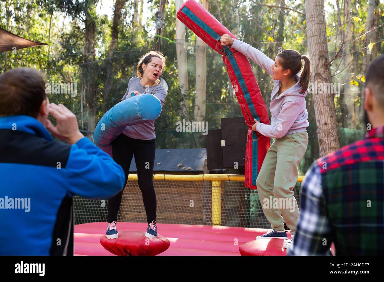 Two smiling women having funny battle by big stuffed beams on ...