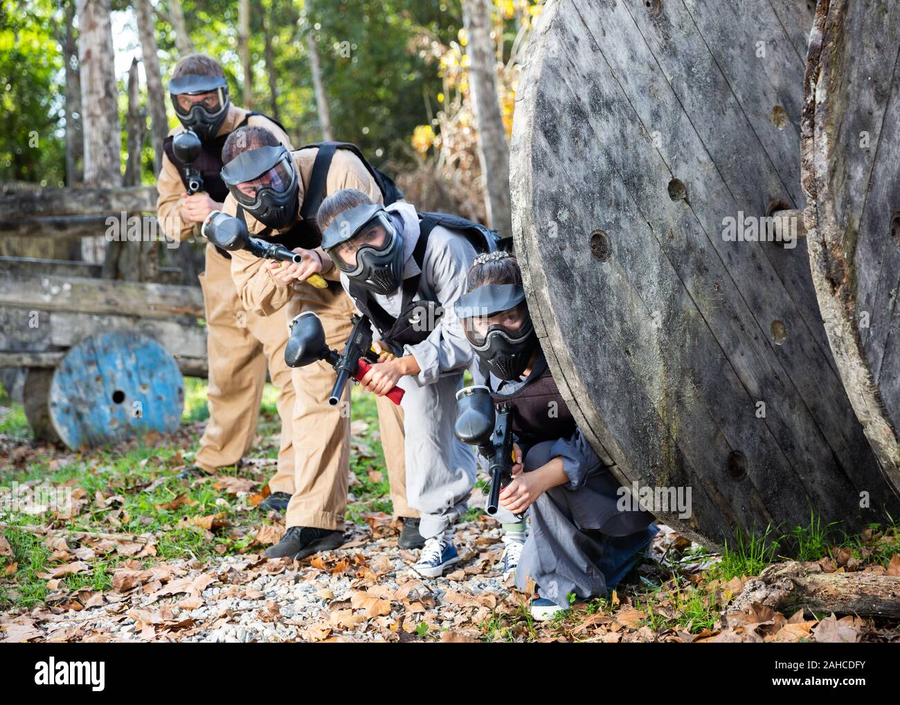 Excited male and female paintball players in protective uniform aiming ...