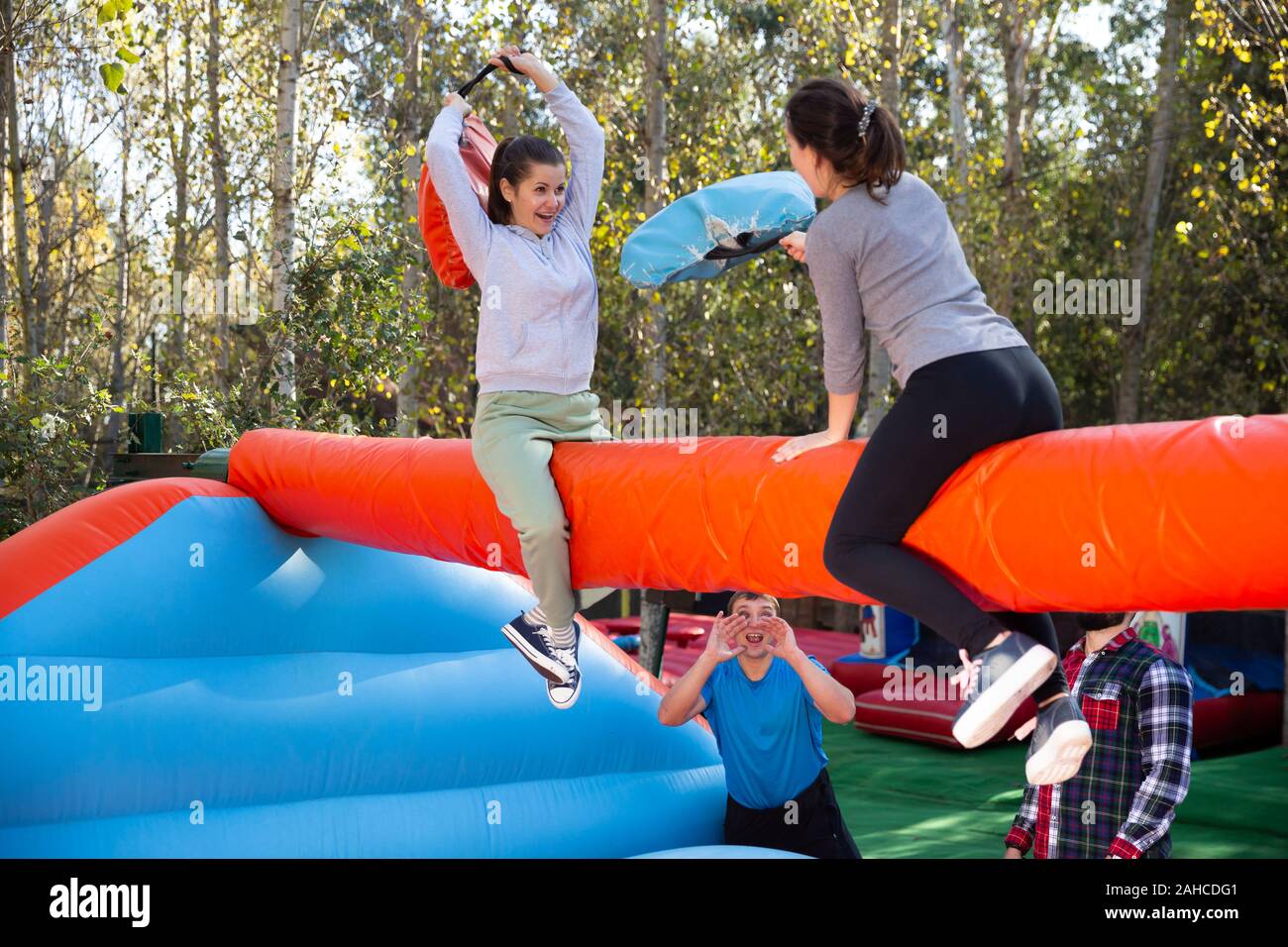 Female friends having funny wrestling by pillows on inflatable beam in ...