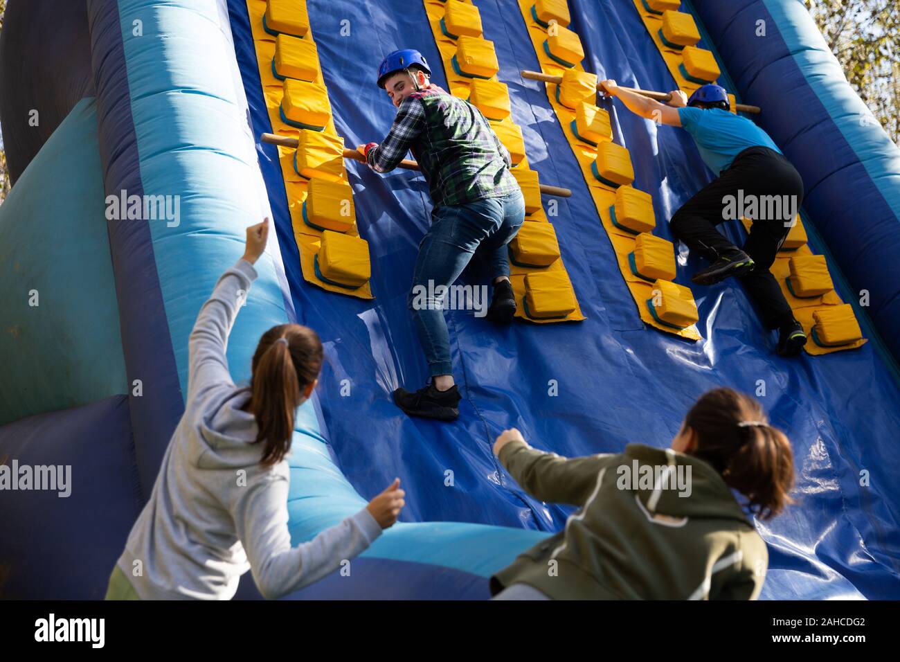 Group of excited people passing obstacles on inflatable arena at ...