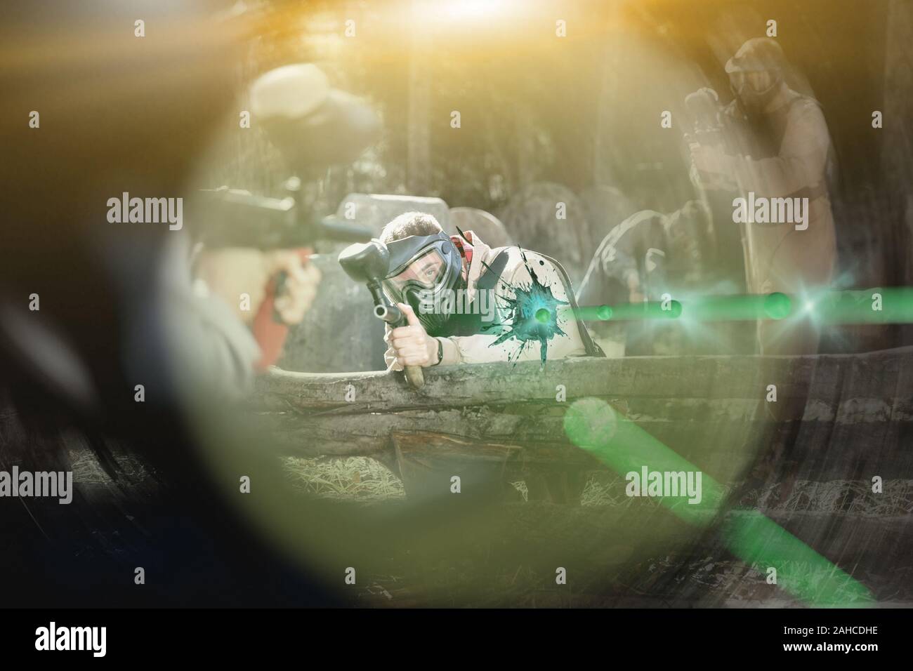 Team of male and female paintball players with marker guns aiming on ...