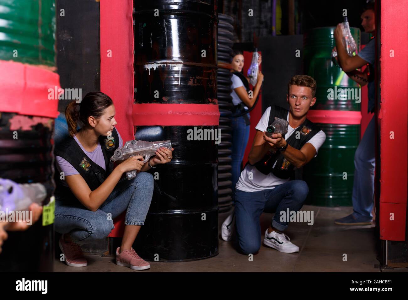 Group portrait of fine emotional people with laser guns playing laser ...