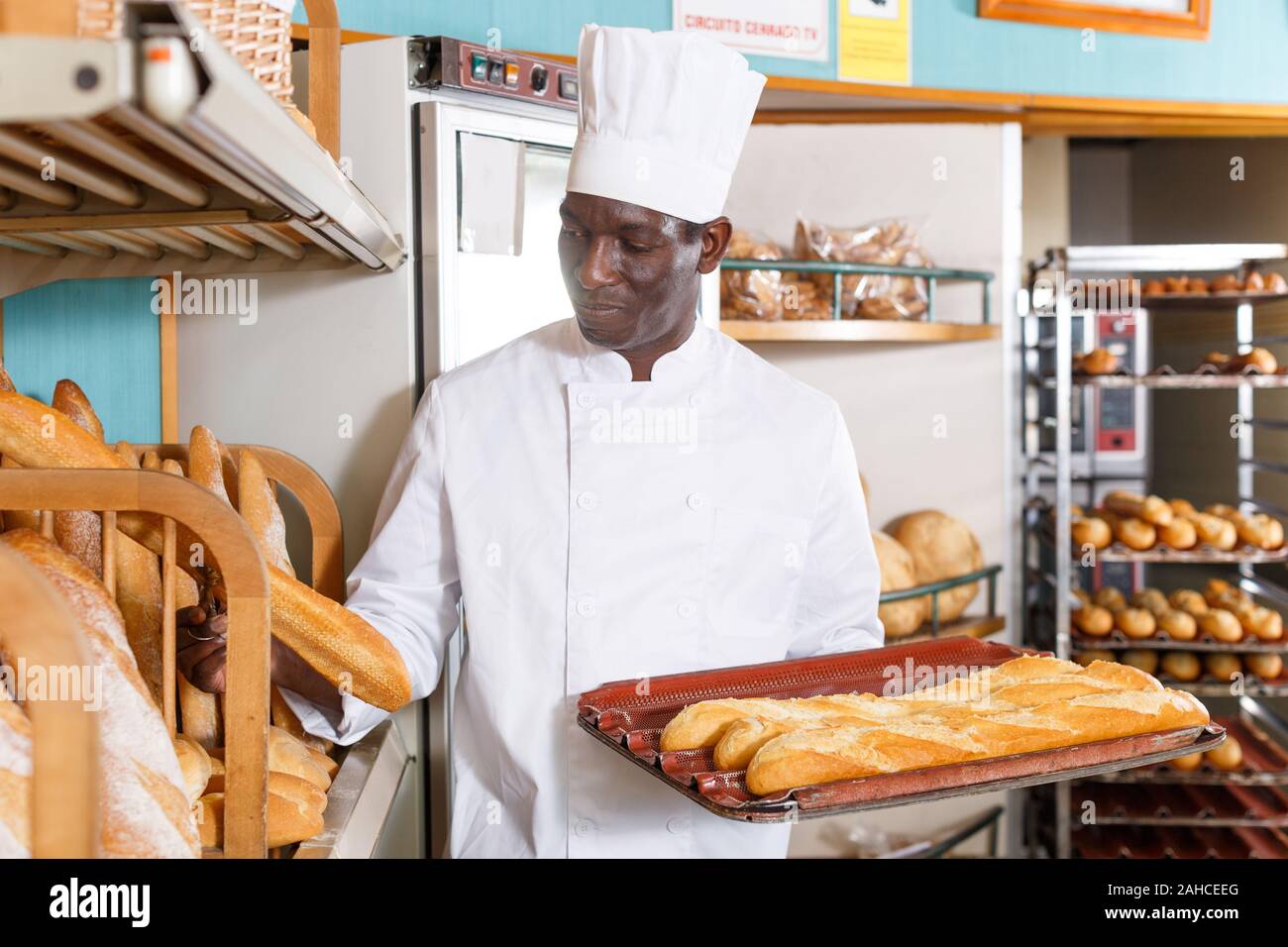 Skillful African American baker working in small bakery, arranging ...