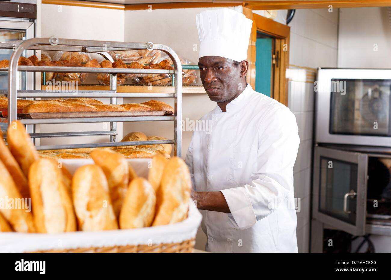 Skillful African American baker working in small bakery, carrying fresh ...