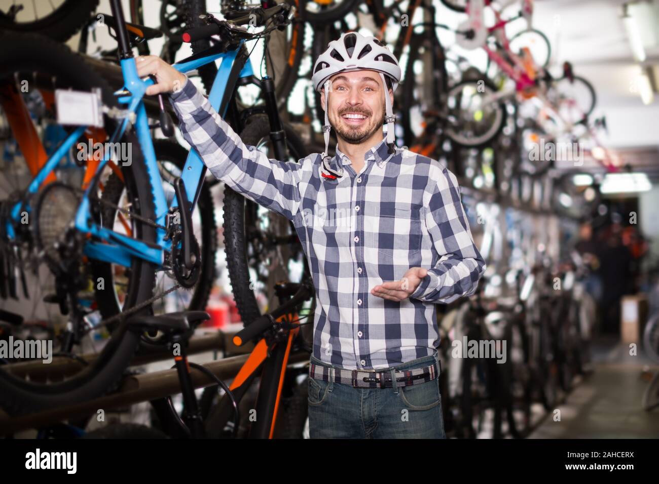 attractive man in helmet chooses for himself sports bike in bicycle ...