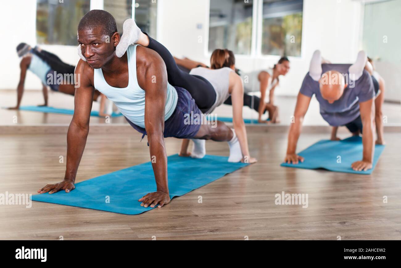 Group of sporty people doing stretching exercises in pairs before a ...