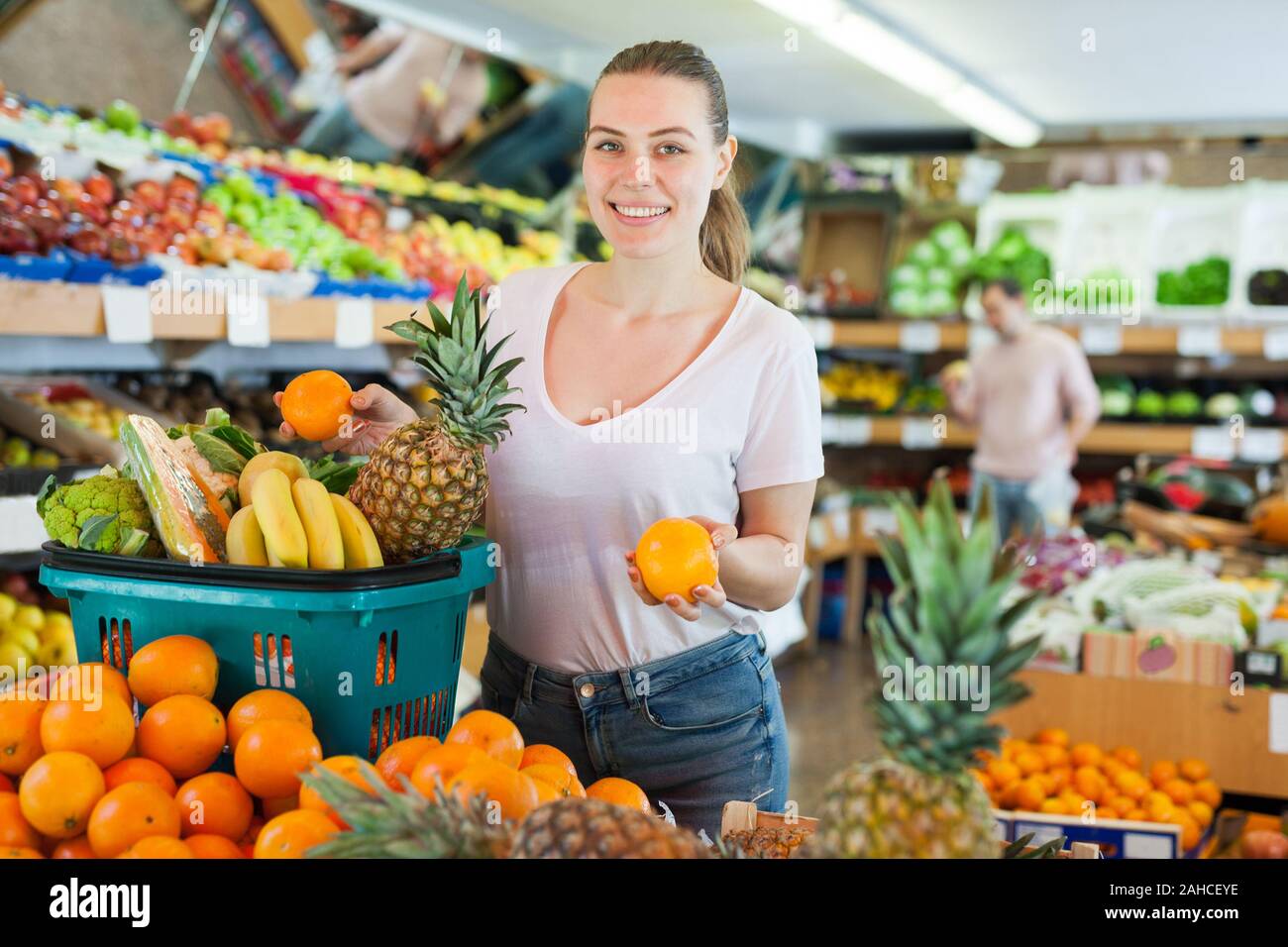 Young woman standing with full grocery cart during shopping in fruit ...
