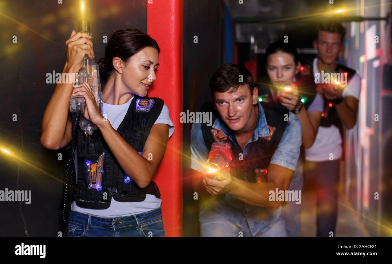Group positive emotional people with laser guns playing laser tag game ...
