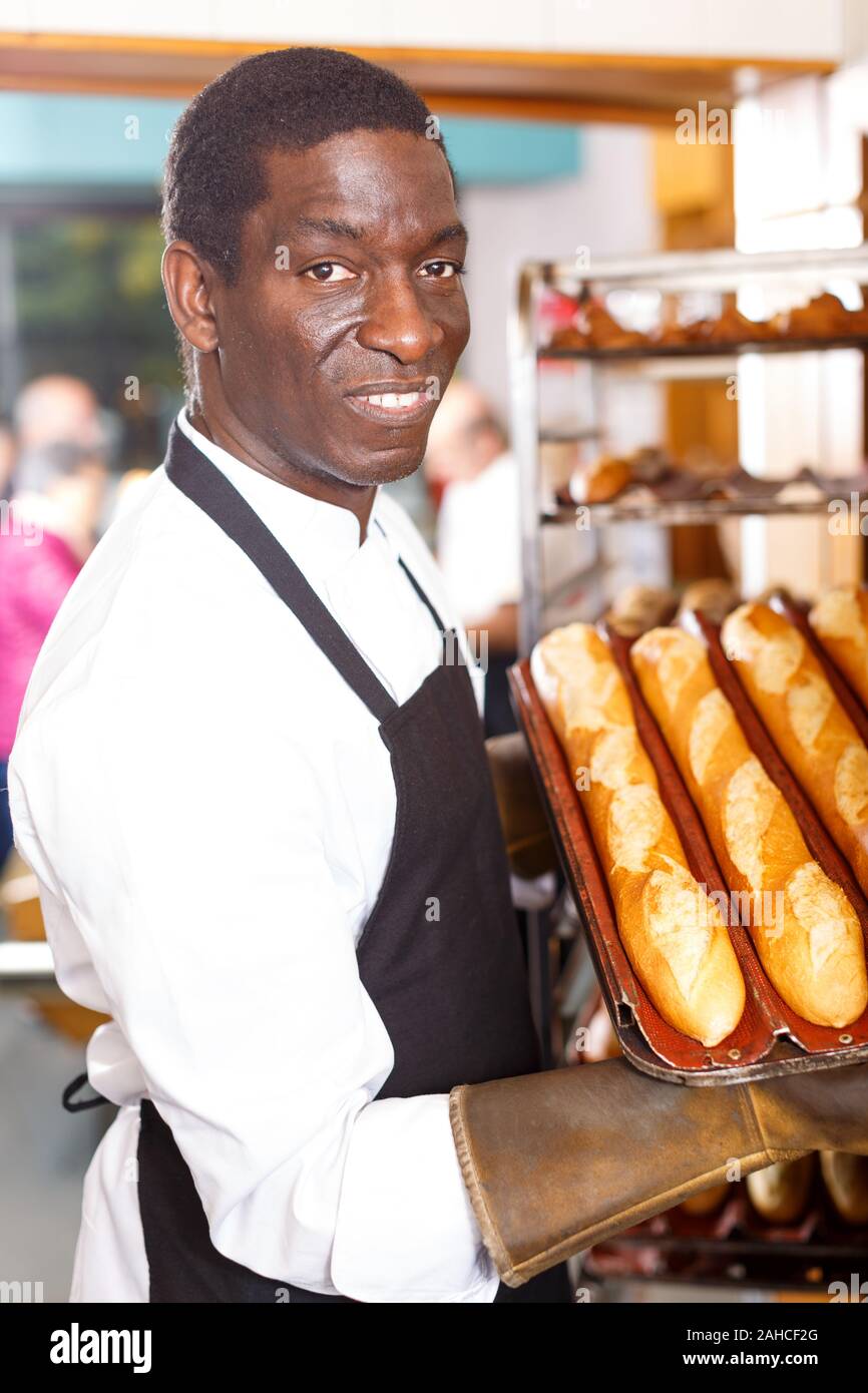Portrait of successful owner of bakery holding tray with fresh ...