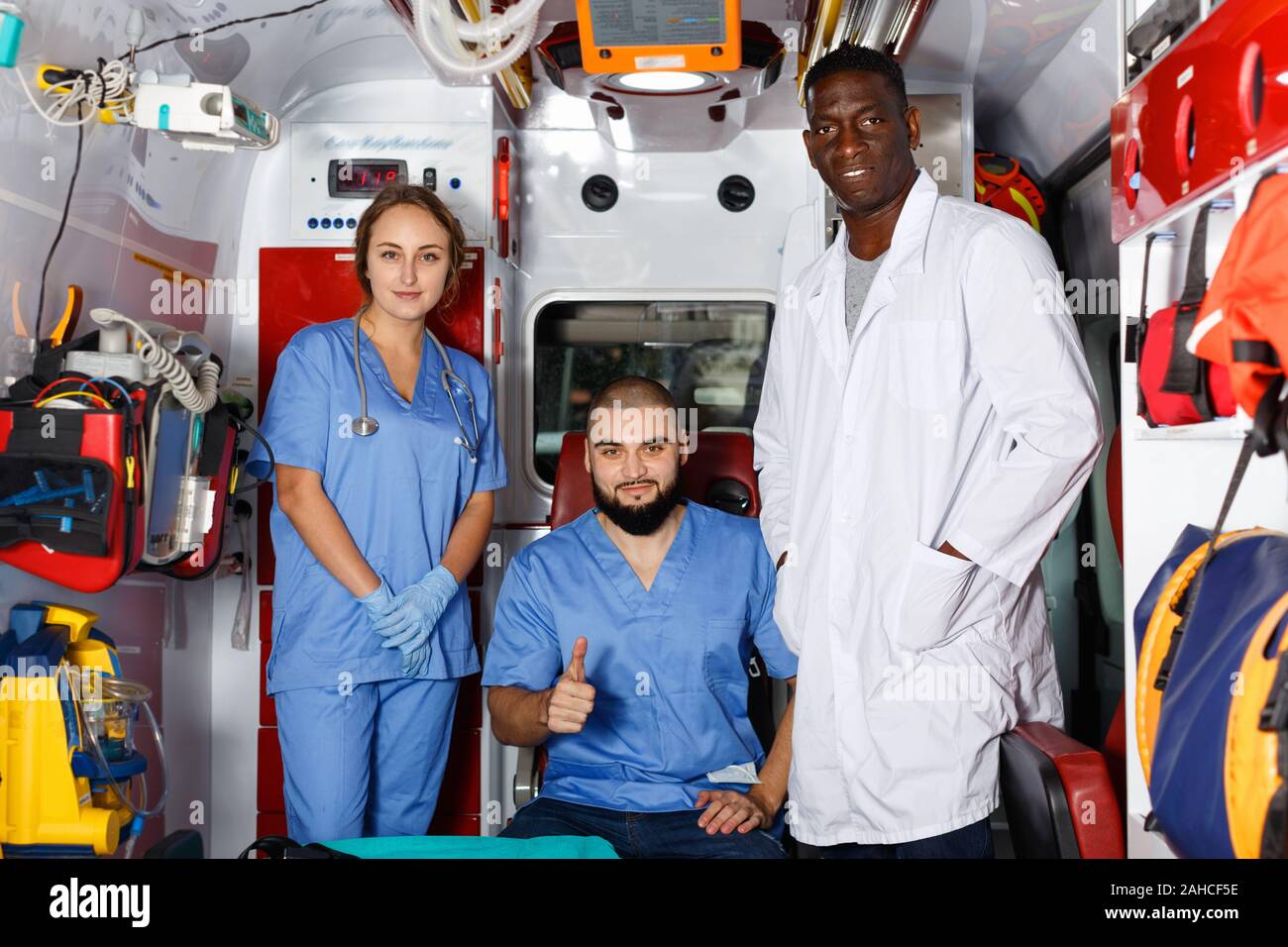 Three positive friendly smiling efficient ambulance doctors posing in ...