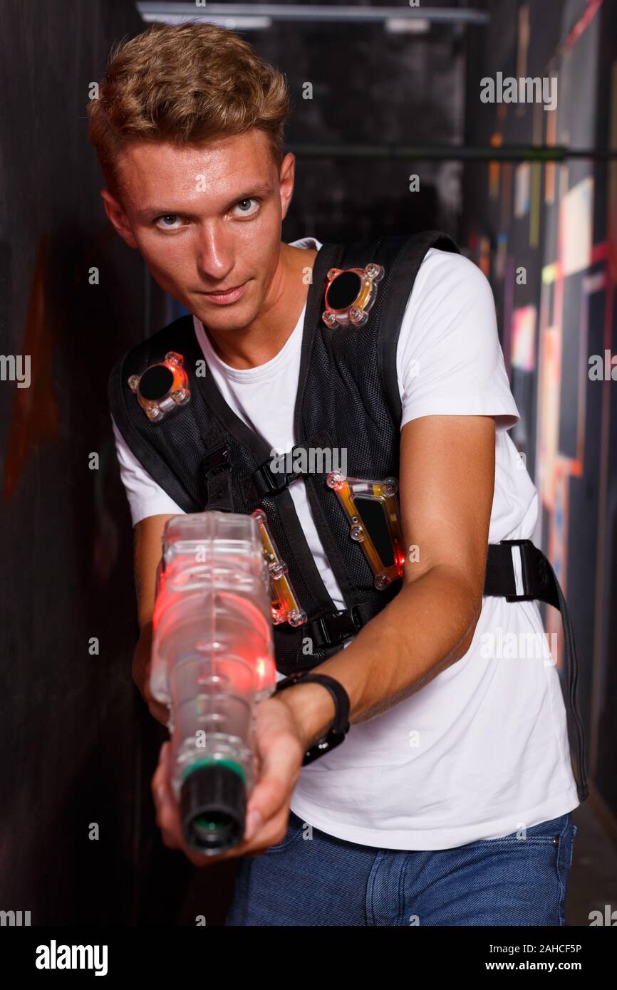 Young man standing with laser gun and took aim during laser tag game in ...