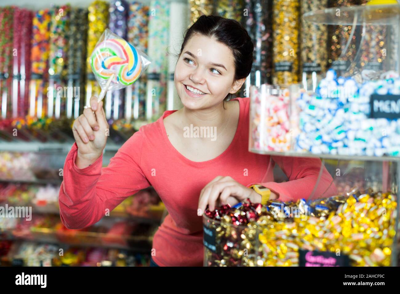 Happy brunette girl buying candies at shop Stock Photo - Alamy