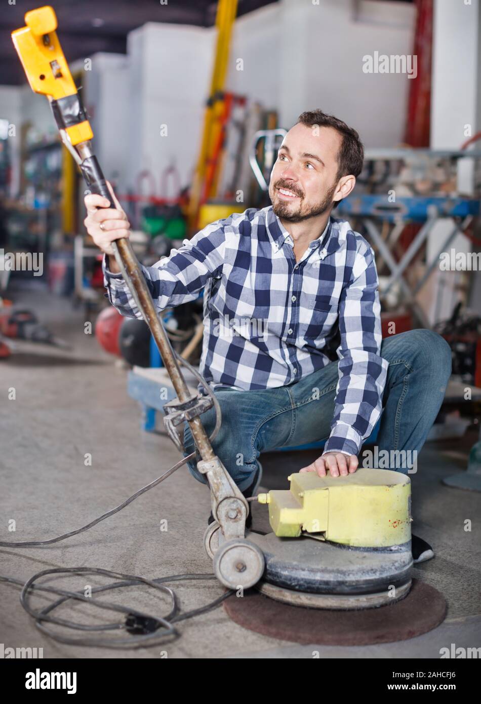Smiling working man practicing his skills with disk sander in a ...
