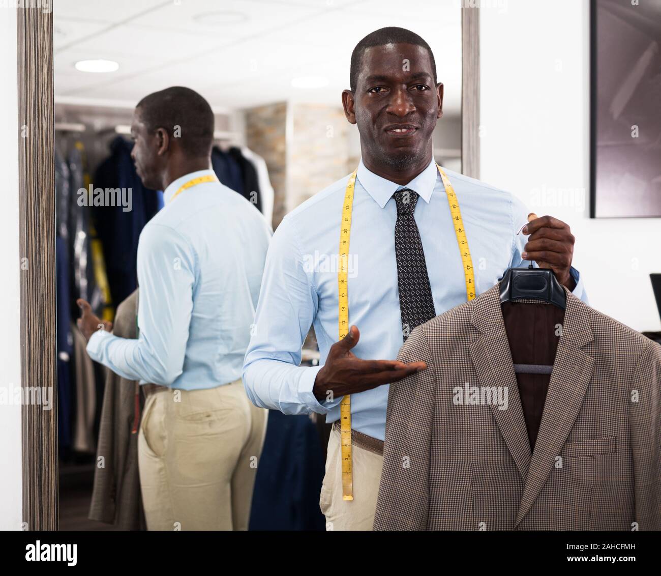 Male customer demonstrating his choice of suit in shop Stock Photo - Alamy