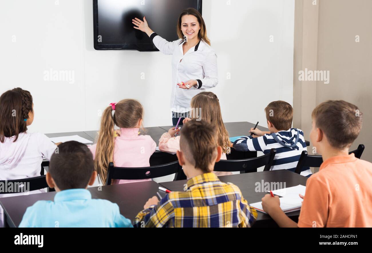 Positive little boys and girls with teacher in classroom Stock Photo ...