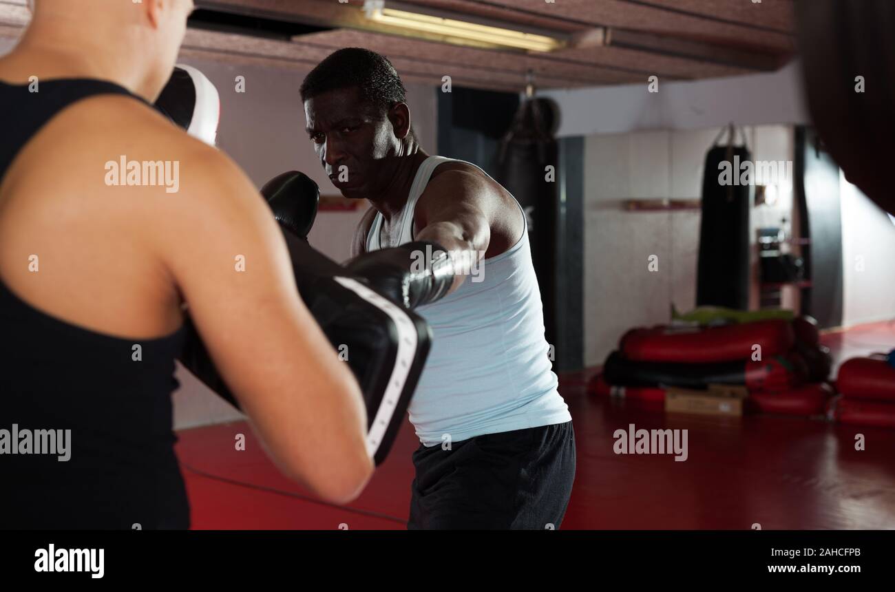Trainer assisting african american in boxing Stock Photo - Alamy