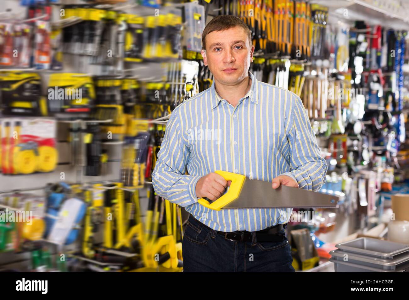 Cheerful male customer choose hacksaw at hardware store Stock Photo - Alamy
