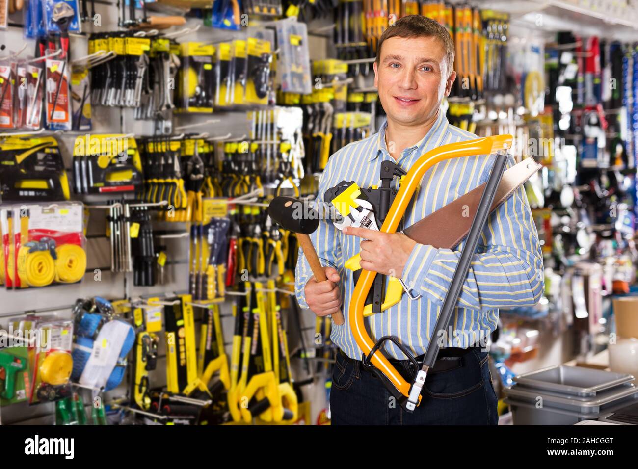 Happy male customer holding purchases in tools store Stock Photo - Alamy