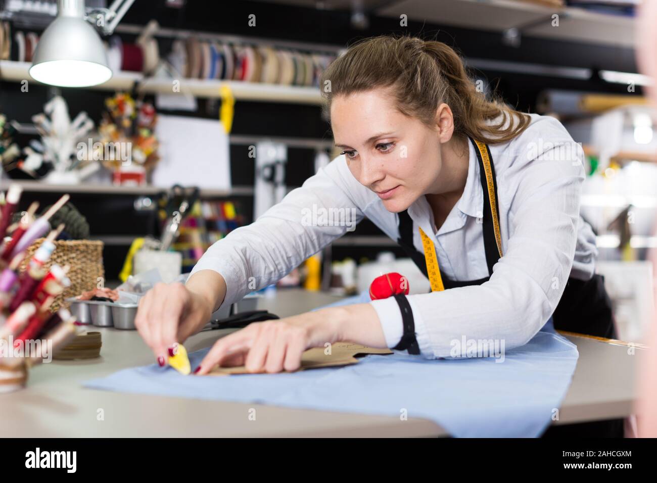 Female seamstress is cutting textile for create new dress in the ...