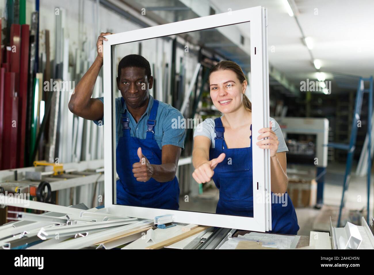 Portrait of man and woman worker who are standing with window frames in ...