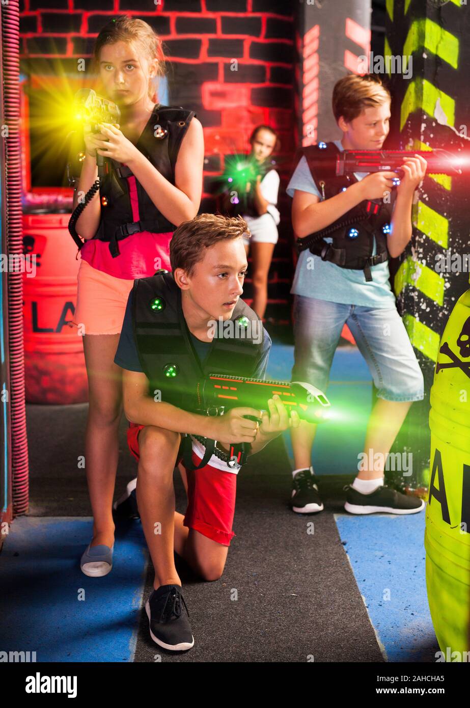 Group of happy teenagers with laser guns having fun on dark lasertag ...