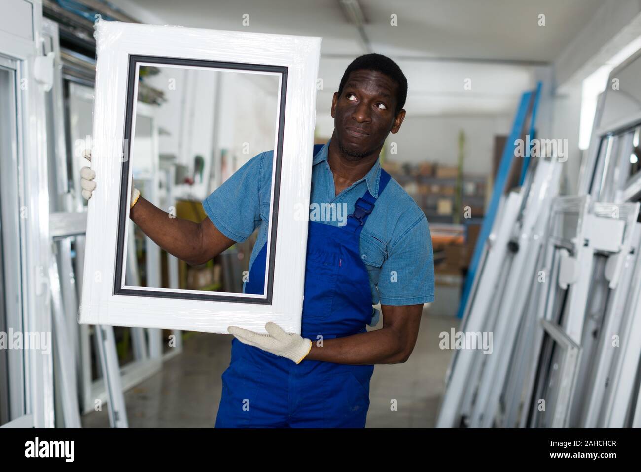 Portrait of man worker who is standing with window frame in the pvc ...