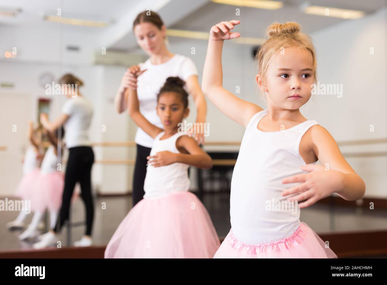 Two little girls practicing choreographic elements in ballet hall Stock ...