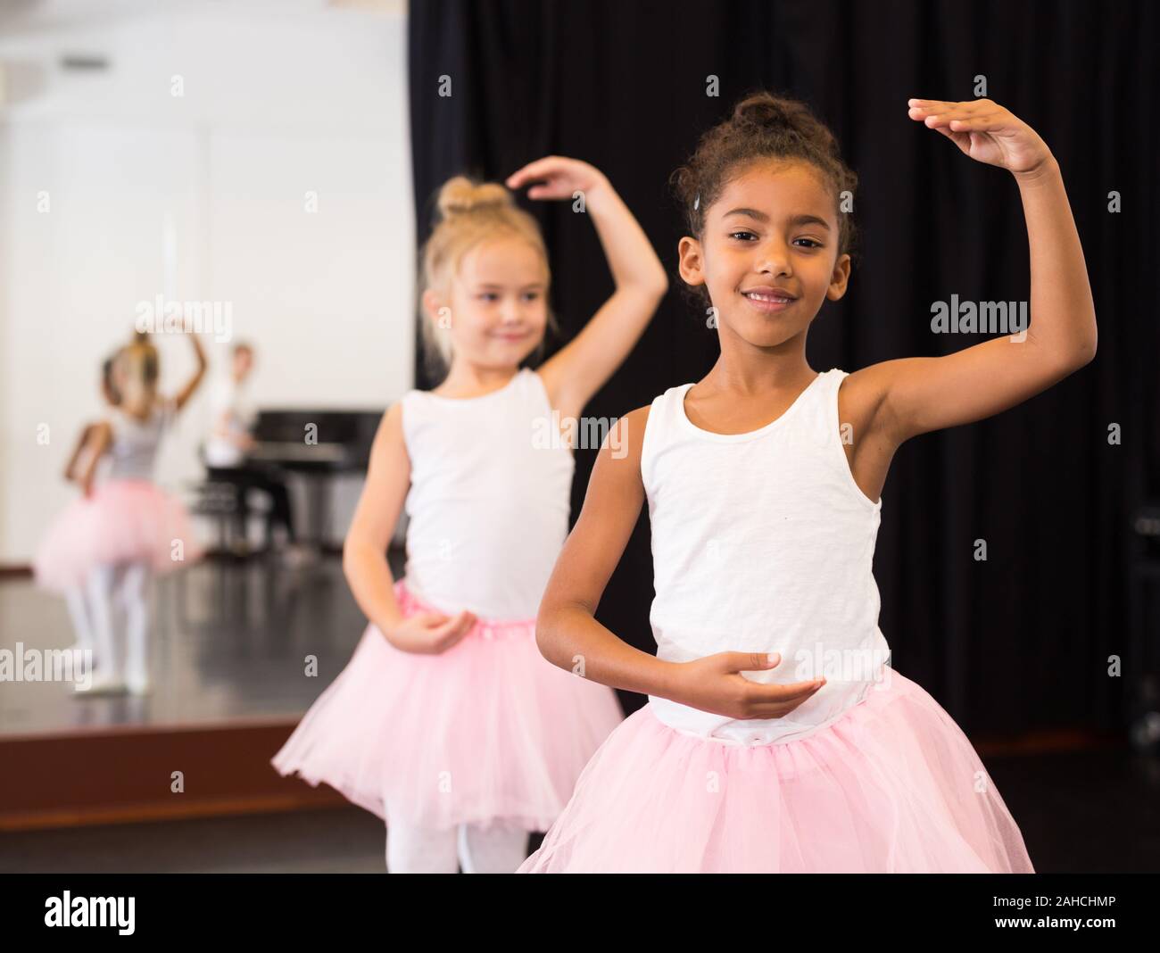 Two little girls practicing ballet elements and positions in dance ...