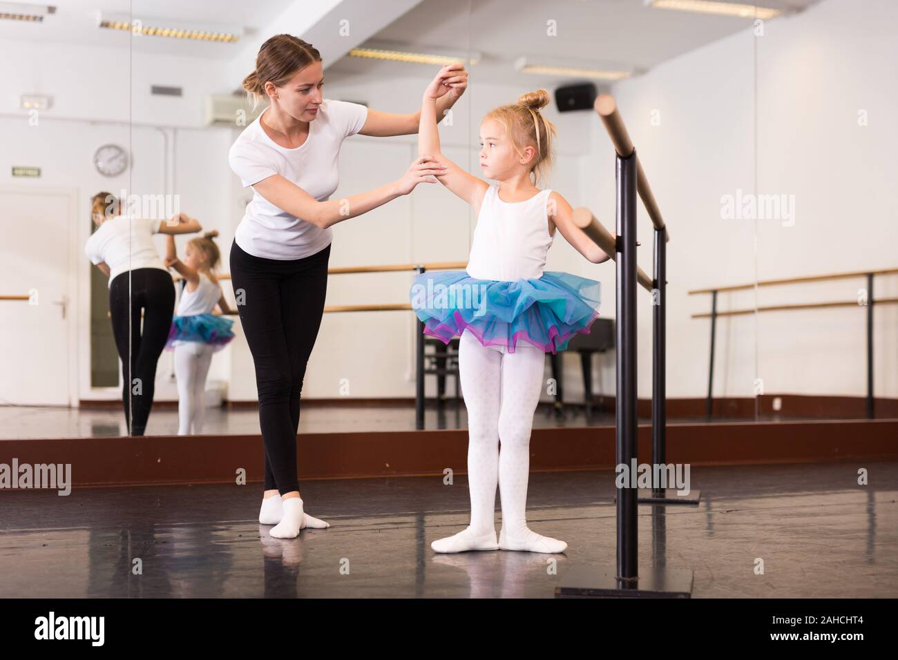 Female classical dance trainer teaching little ballerina in ballet ...
