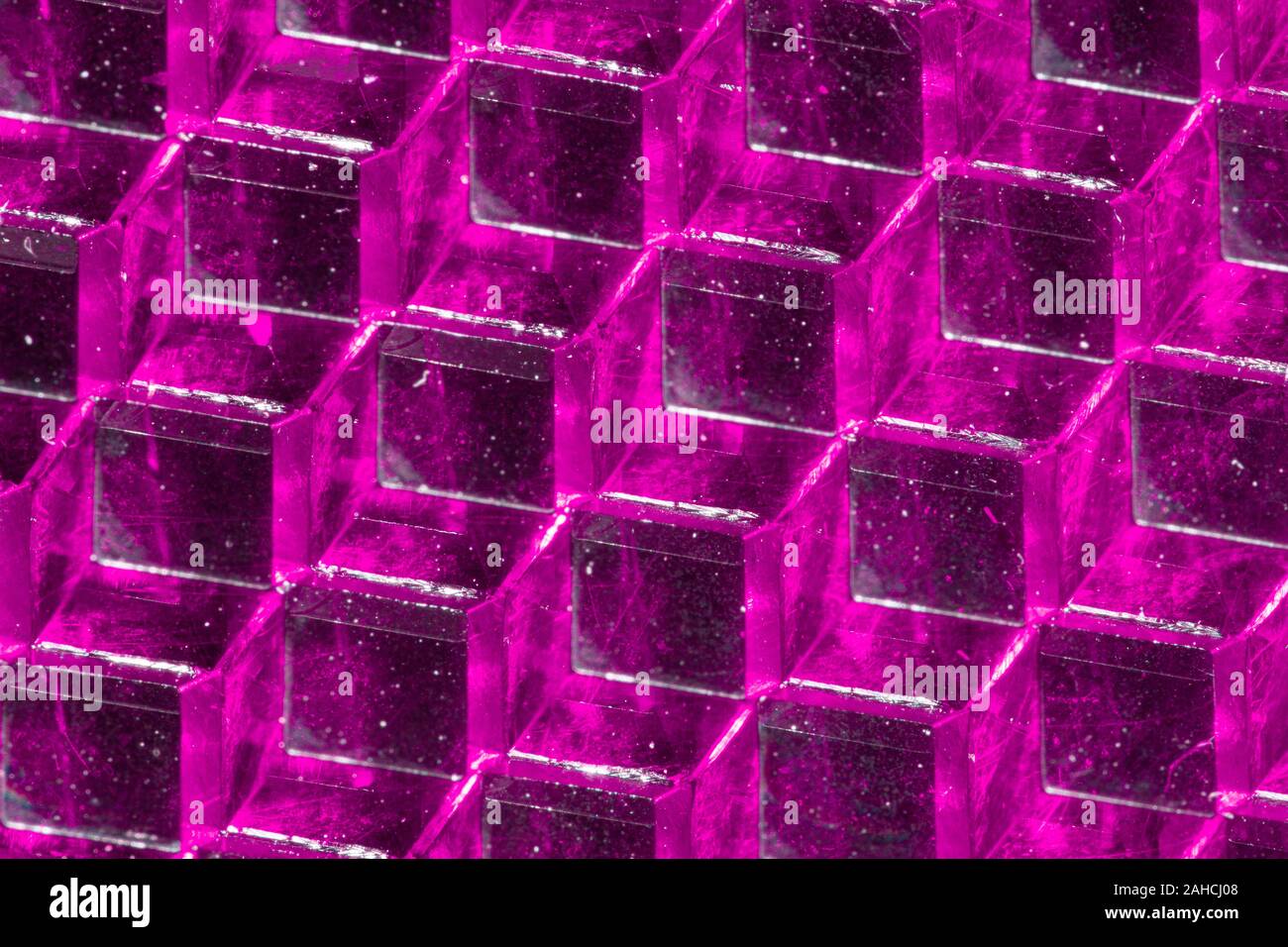 A close up abstract macro photo of a plastic reflector lit with a pink ...