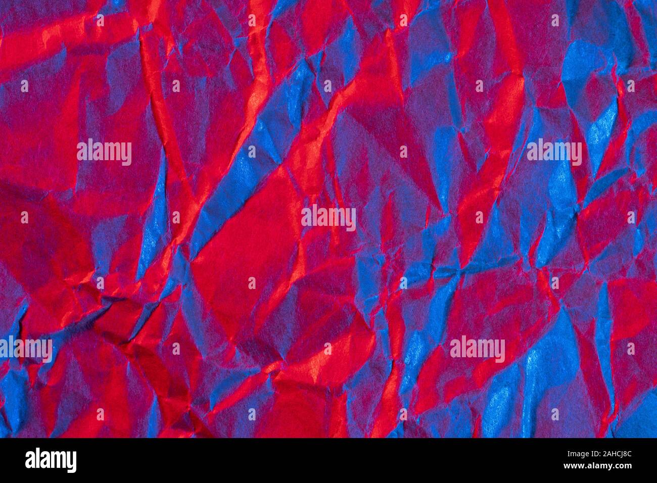 A close up abstract macro photo of crumpled creased paper lit with red ...