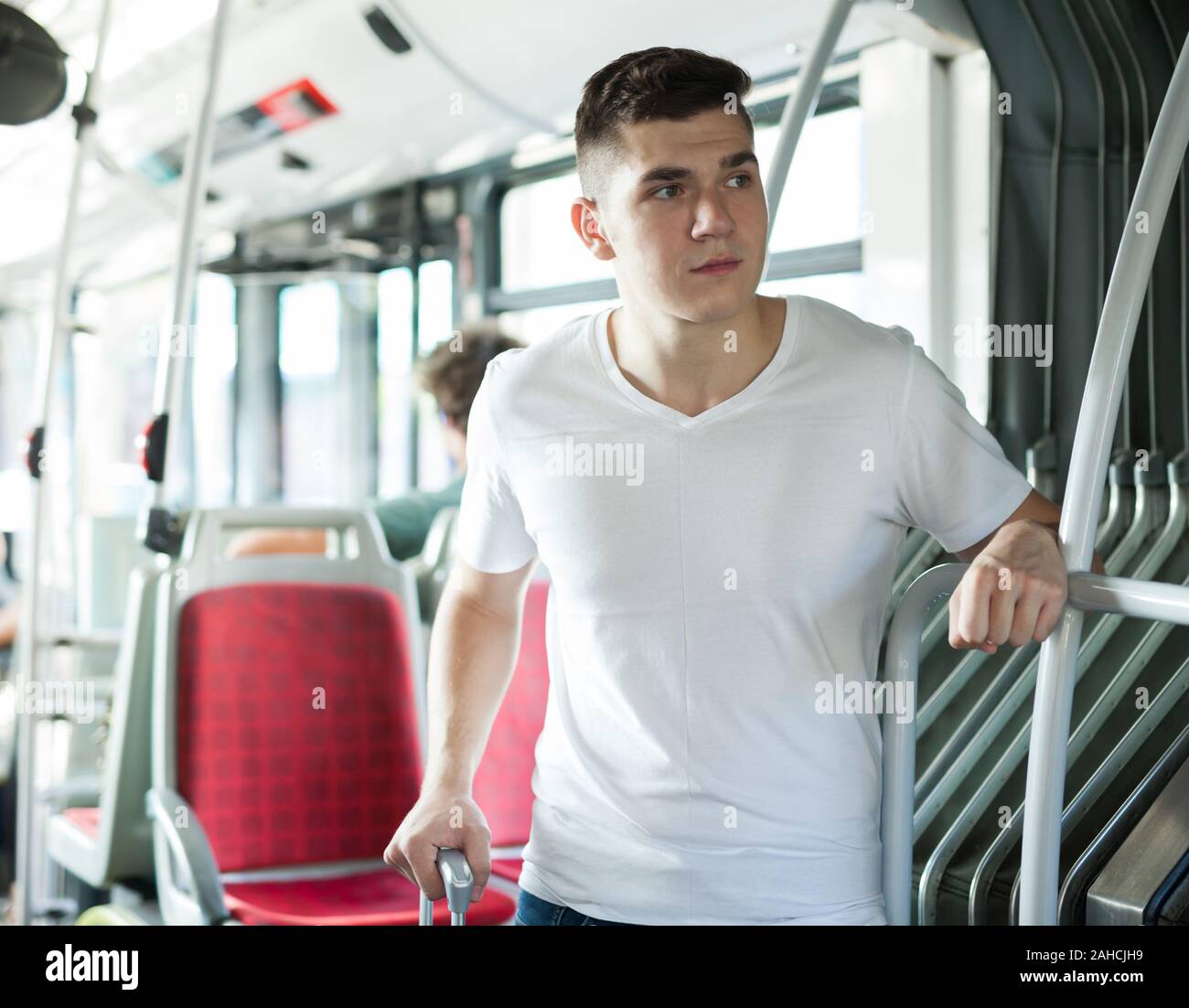 Modern guy standing in public land transport holding on handrail Stock ...