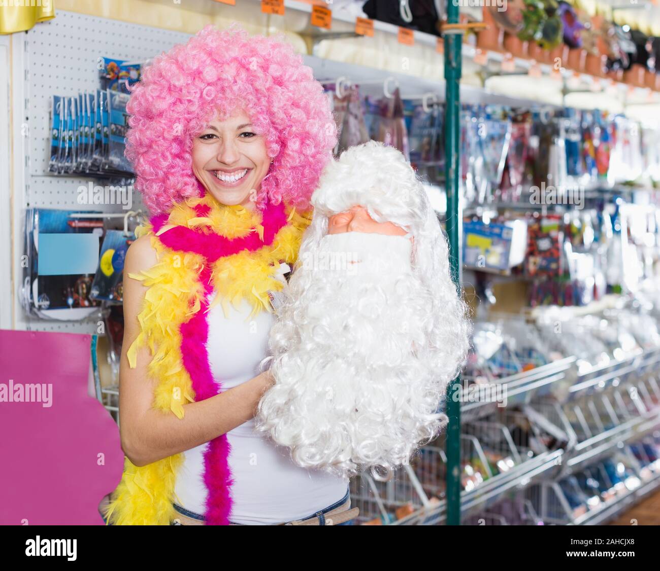 Portrait of young cheerful woman trying on pink clown wig Stock Photo ...