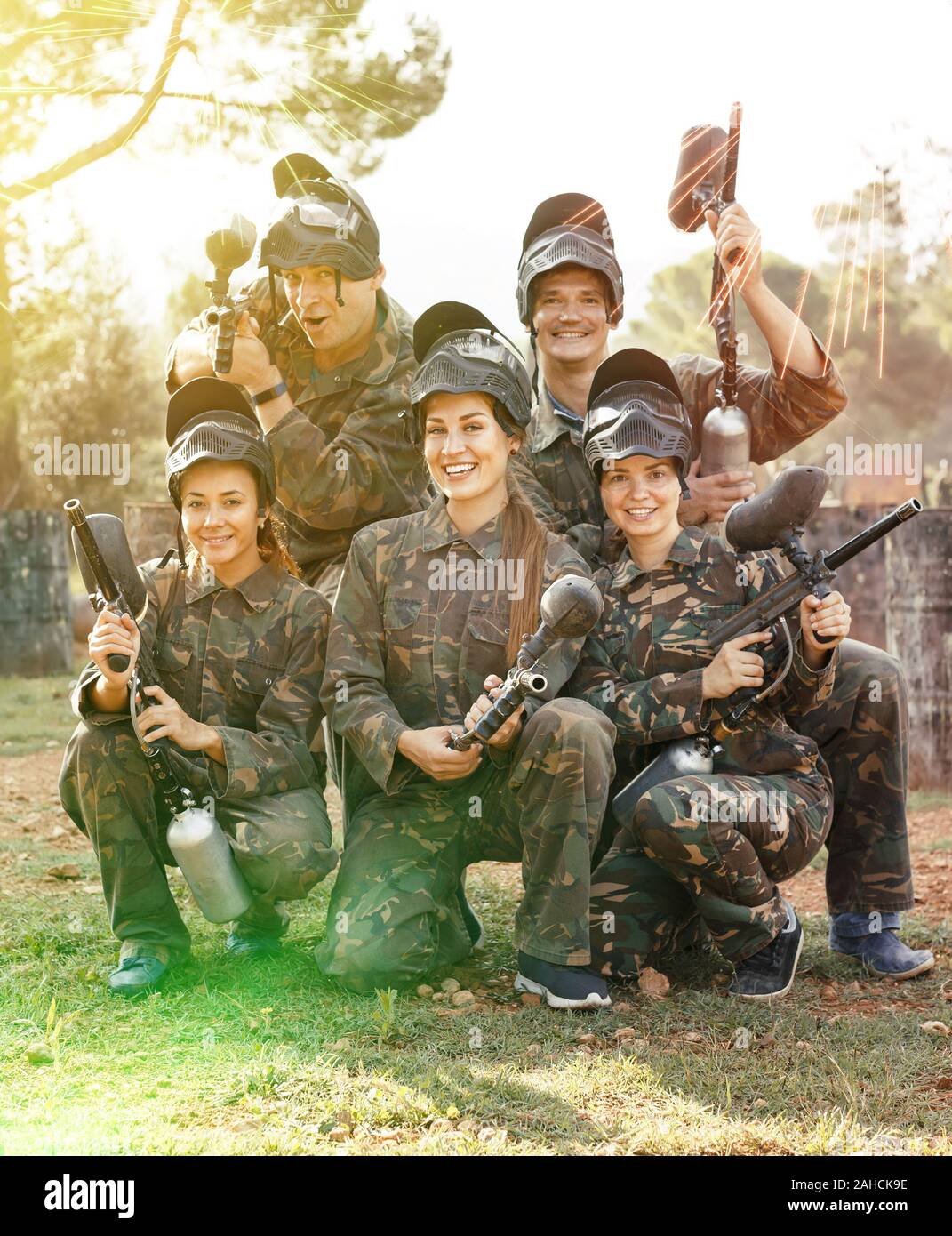 Portrait of joyous team of paintball players with marker guns ready for ...