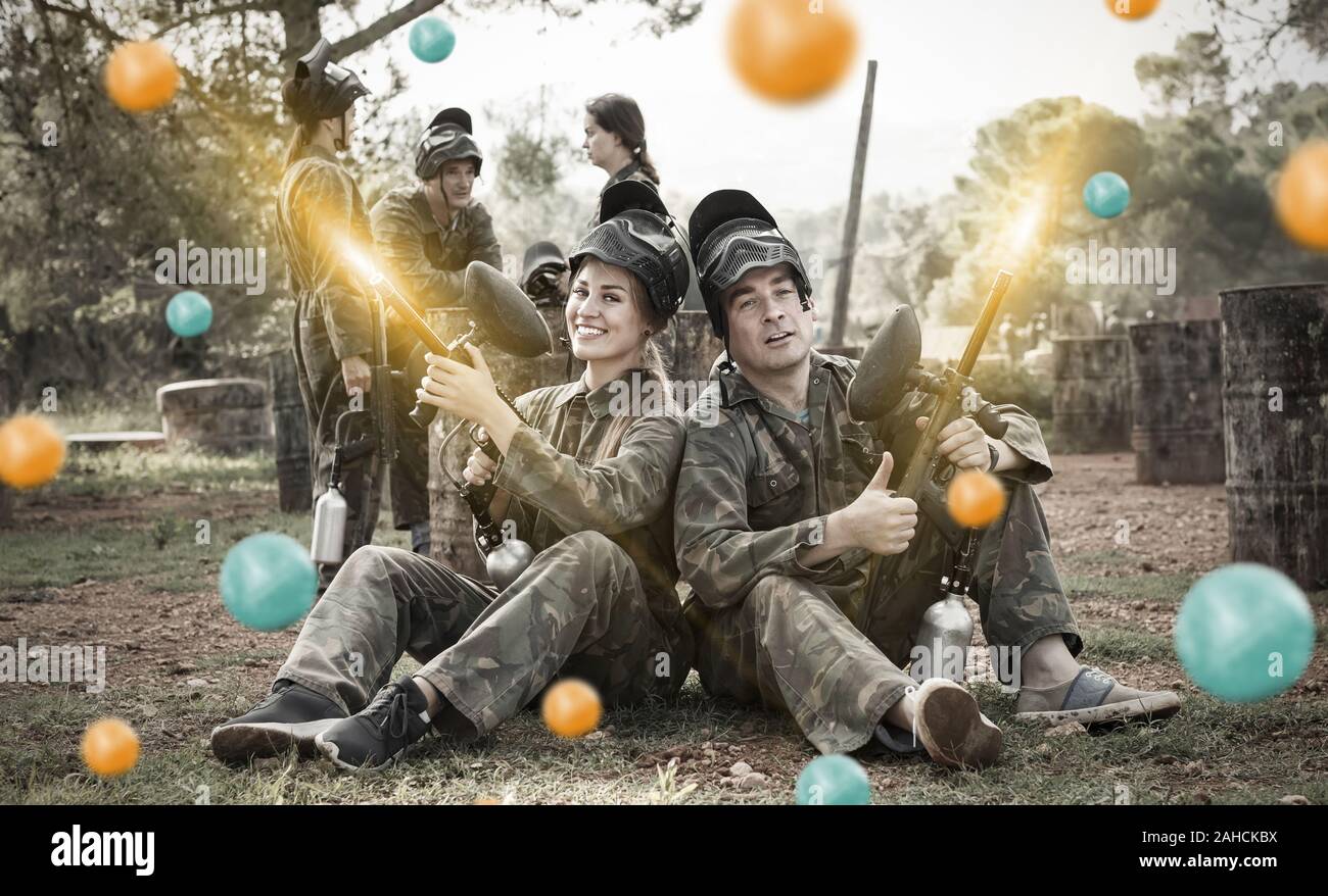 Portrait of positive man and woman paintball players in full gear ready ...