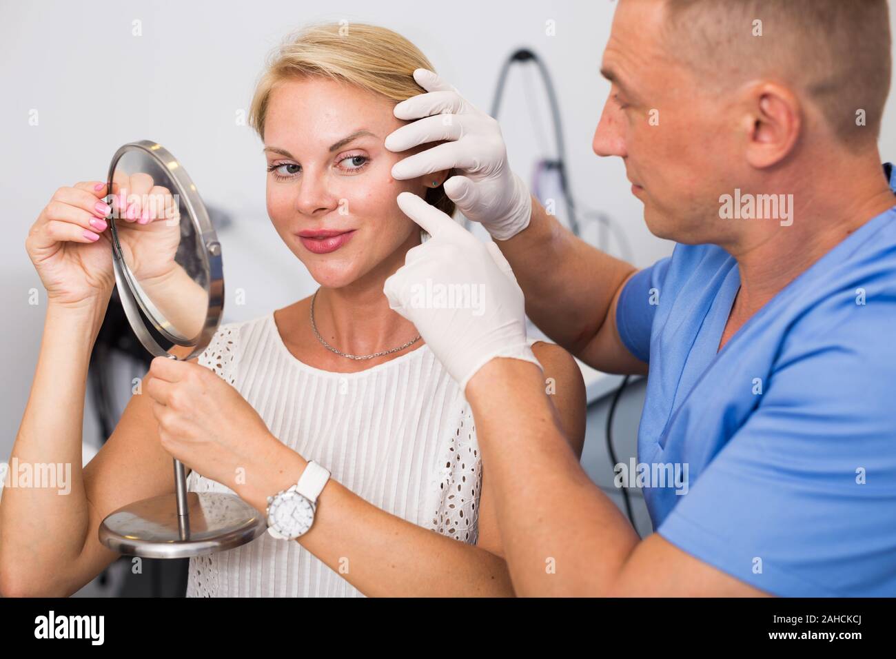 Doctor is examining woman patient behind mirror before the procedure in ...