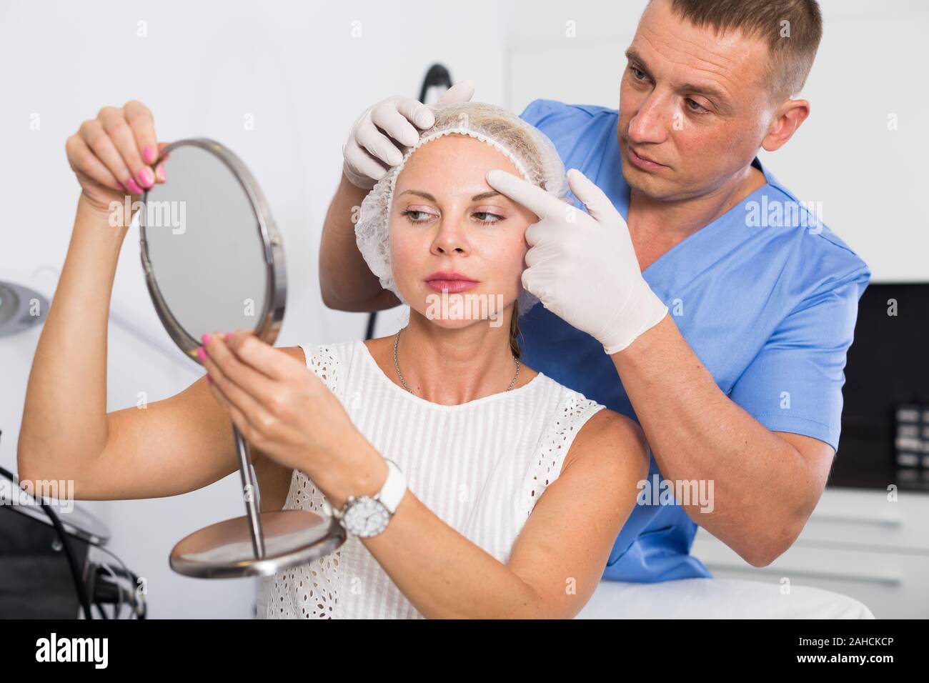 Man doctor is preparing female patient to procedure in cabinet Stock ...