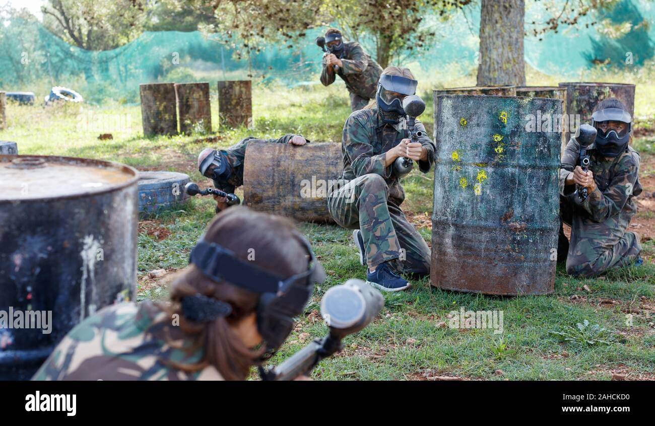 Team of happy cheerful smiling adult people playing paintball on ...