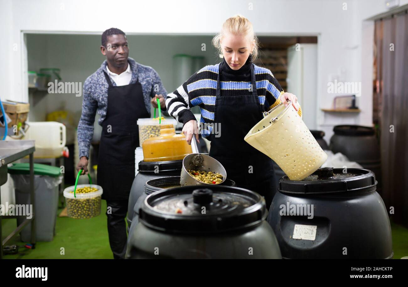 Skillful young woman working in food producing factory, taking pickled ...